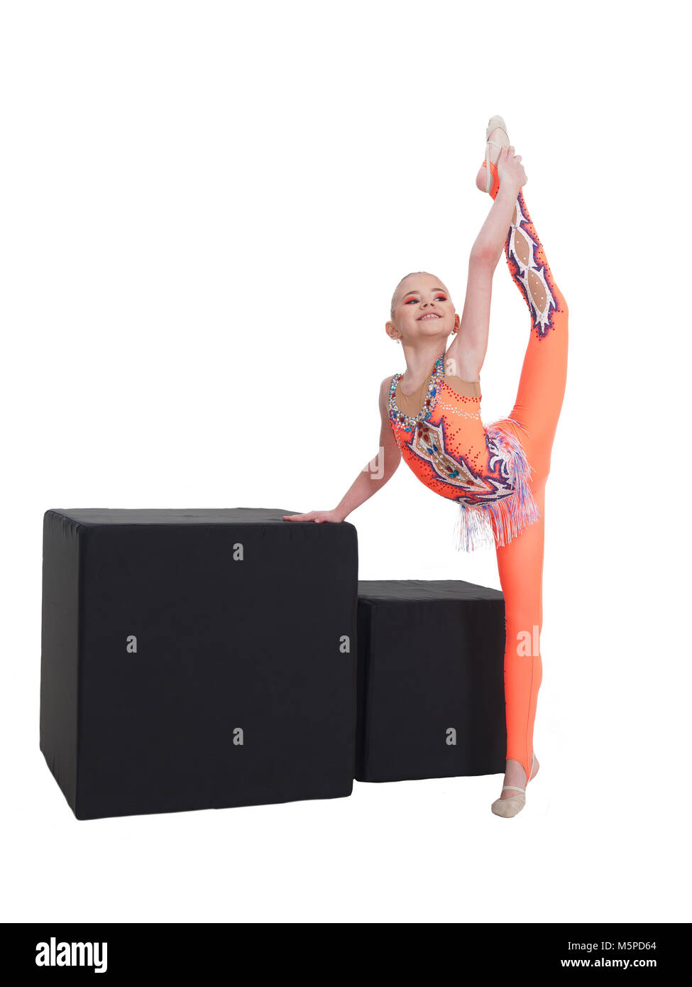 A young gymnast in an orange sports suit stands on a white background ...