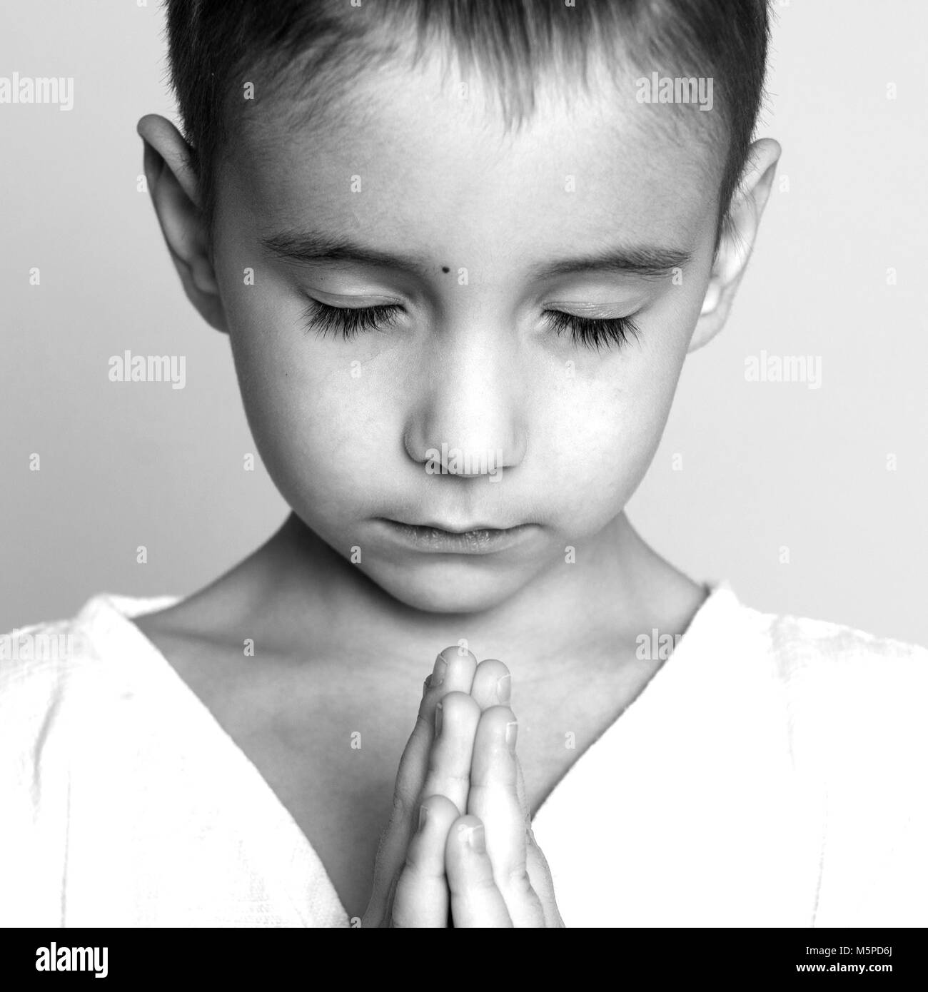 Prayer. Portrait of a beautiful little boy close-up. Black and white ...