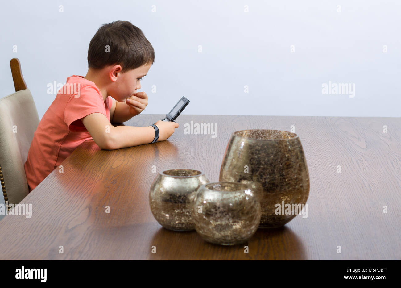 Young boy playing handheld video game at a table with some decoration ...