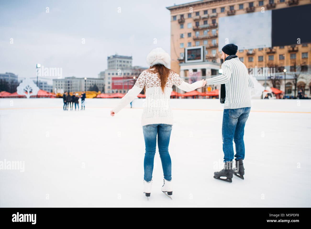 Love couple learn to skate on the rink. Winter skating on open air ...
