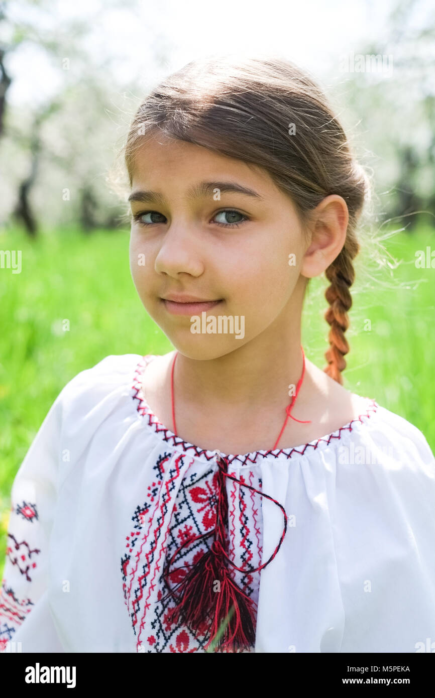 A sweet little girl in embroidery stands in the middle of a flowering ...