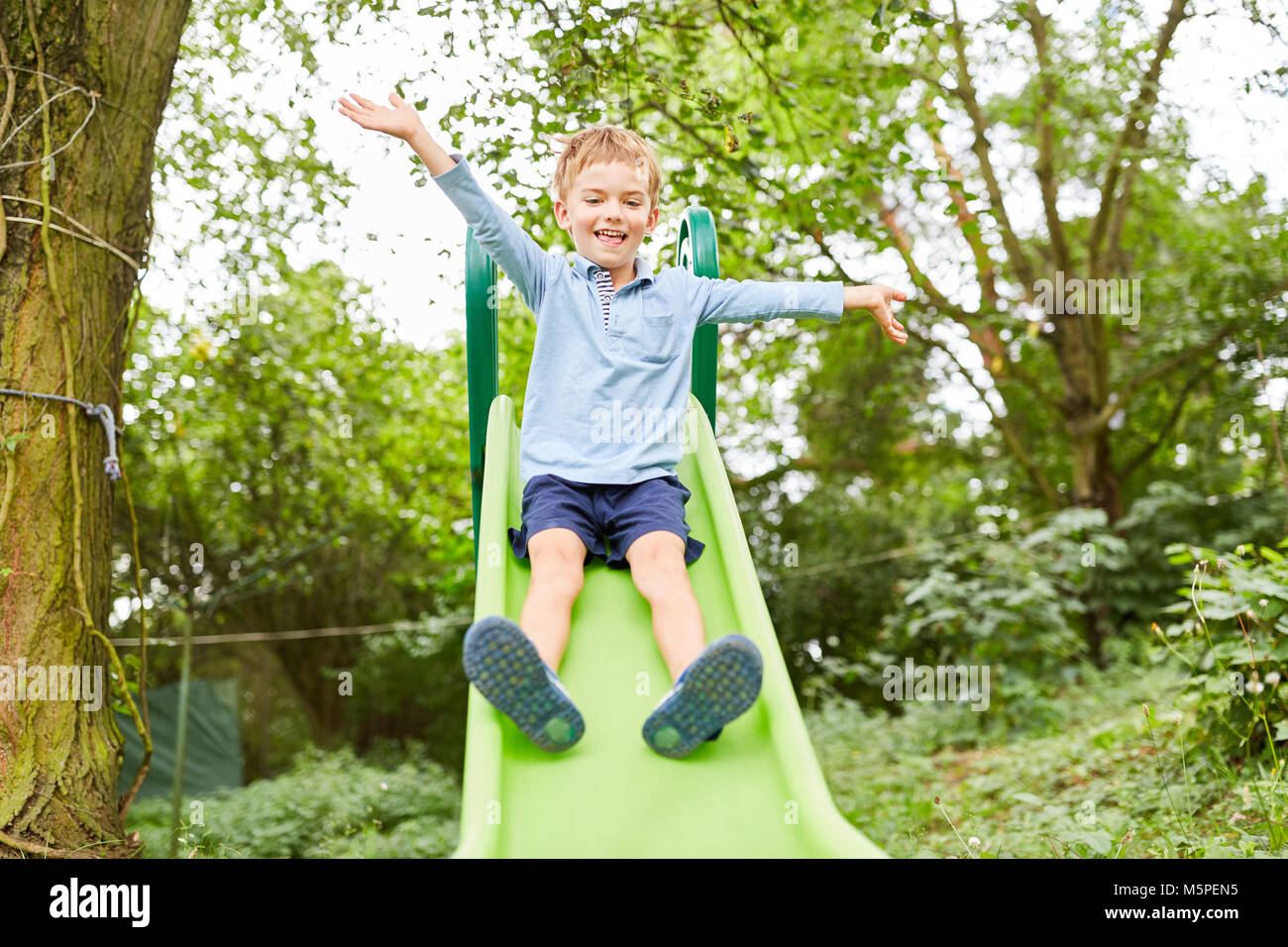 Happy boy on the playground slides down the slide Stock Photo - Alamy