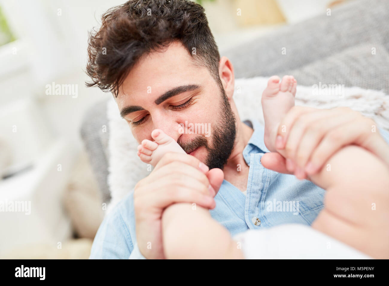 Father lovingly presses his nose against the feet of his newborn baby ...