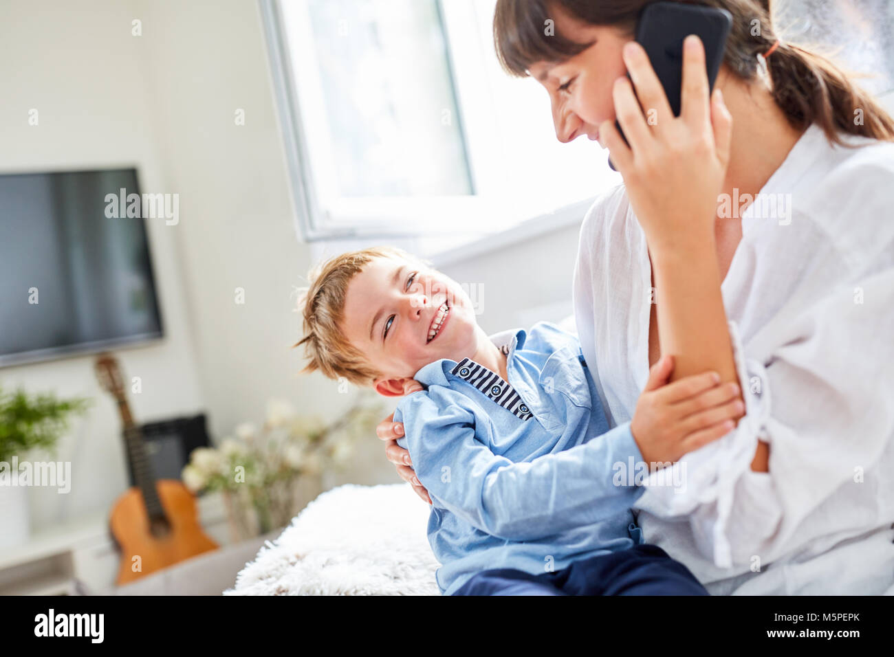 Happy boy is kidding with the mother who is making a phone call Stock ...