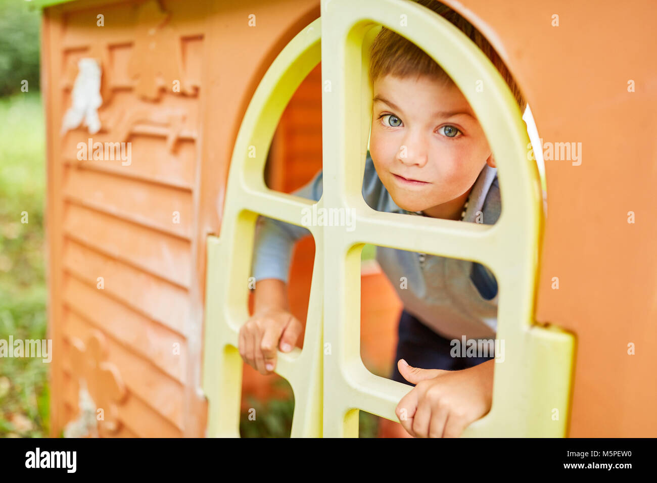 Child looks through a window in the play house on the playground in the ...