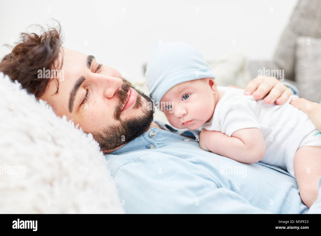 Man as happy father cuddles with newborn baby on the sofa Stock Photo ...