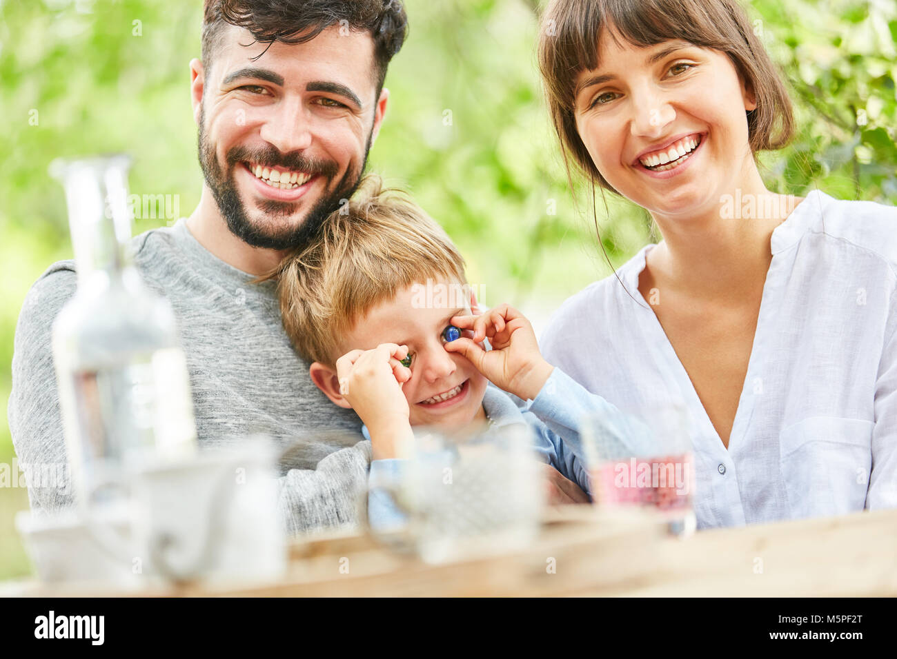 Laughing parents sit in the garden together with their son Stock Photo ...