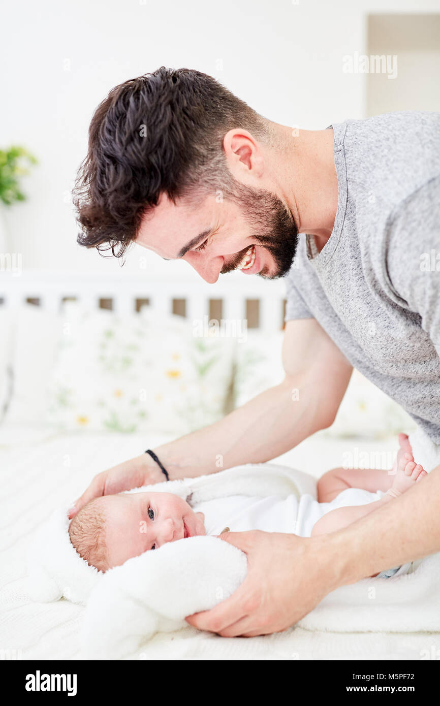Proud and happy father is looking at his newborn baby at home Stock ...