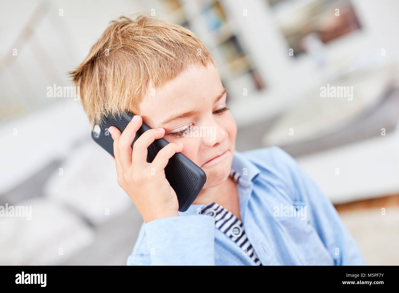 Little boy makes a phone call by mobile phone or smartphone at home ...