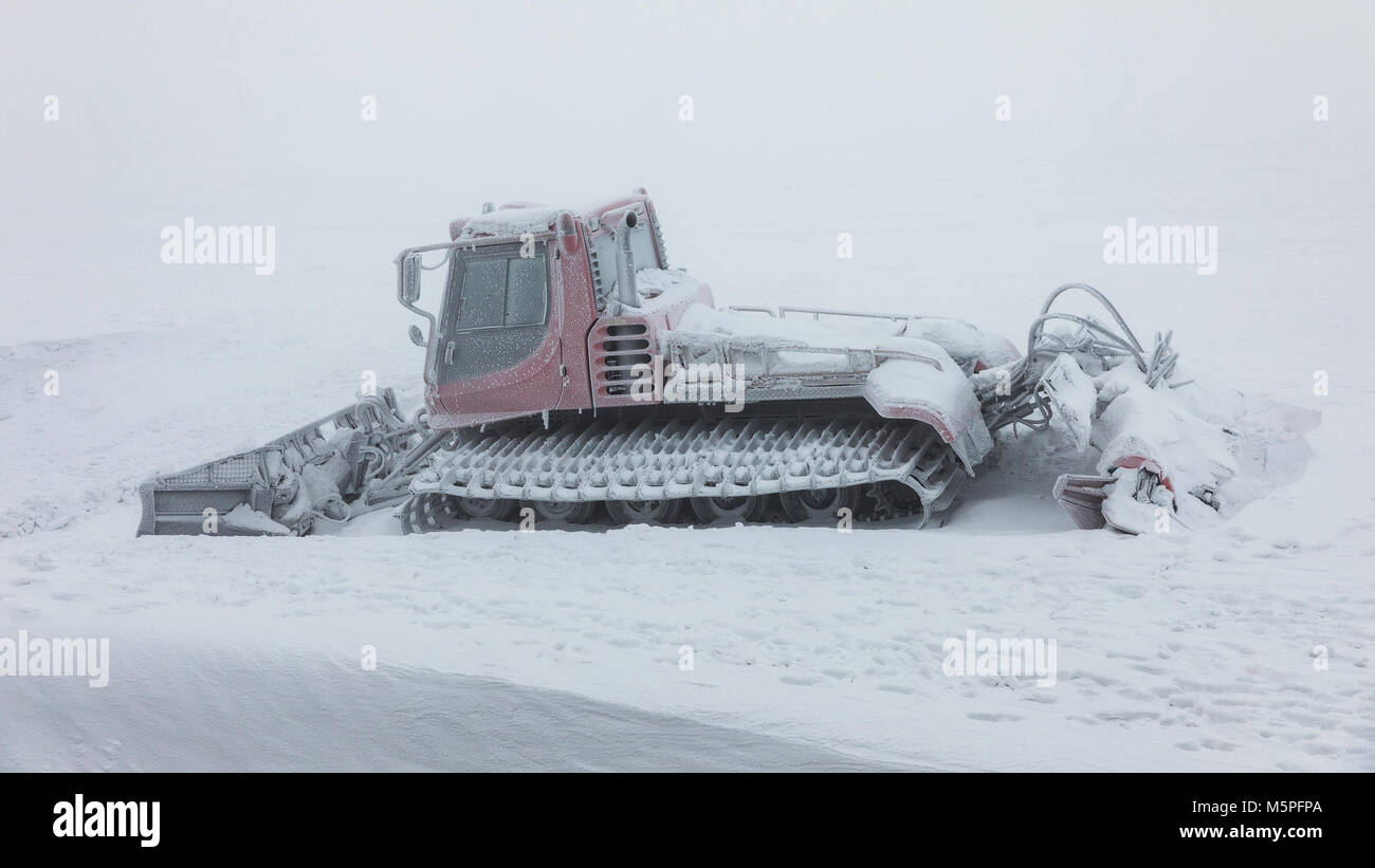 Red ratrak snowcat in winter mountains A red snow tucker covered with ...
