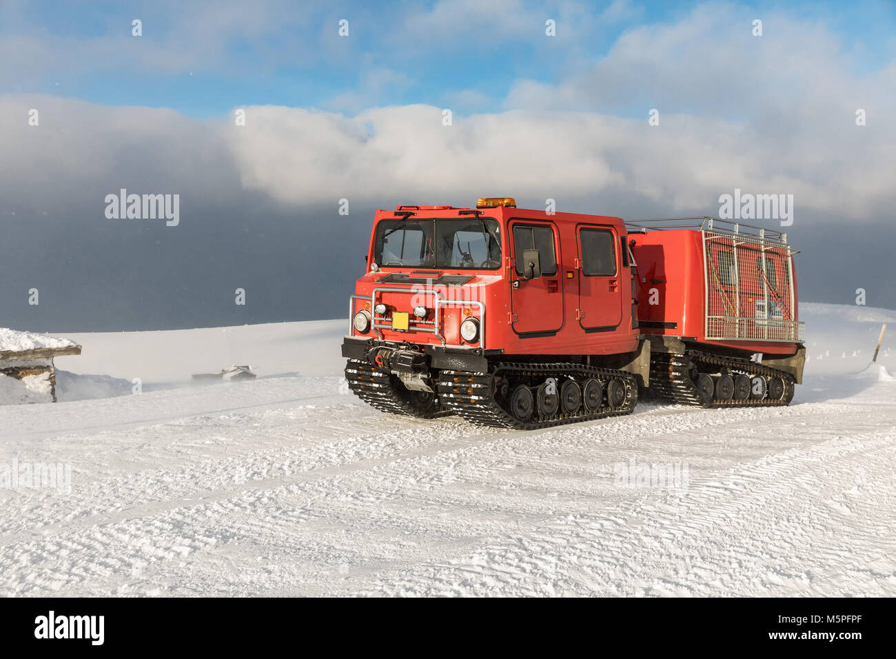 Red ratrak snowcat in winter mountains A red snow tucker covered with ...
