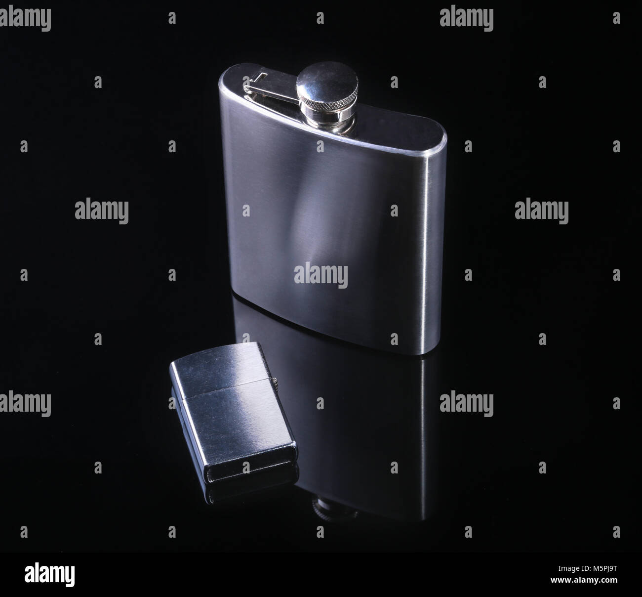 Stainless hip flask and lighter isolated on mirror black background ...
