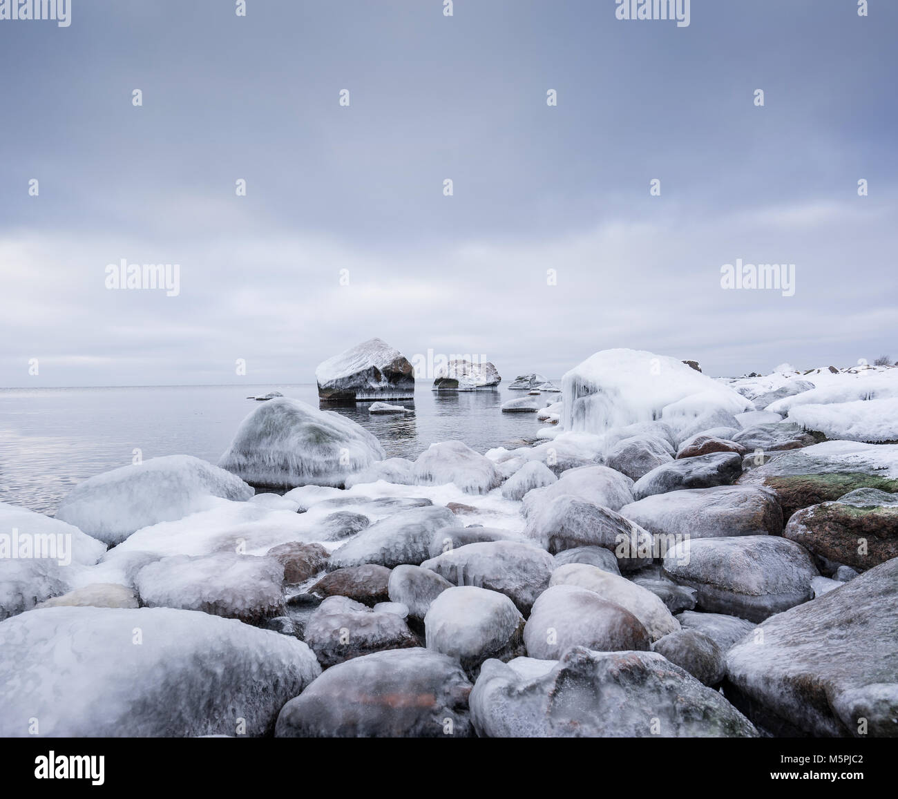Rocky beach on wintertime. Evening light and icy weather on shore like ...