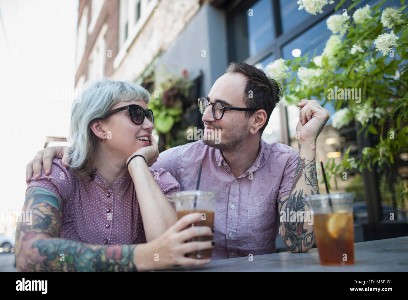 Young couple sitting in outdoor cafe drinking ice tea Stock Photo - Alamy