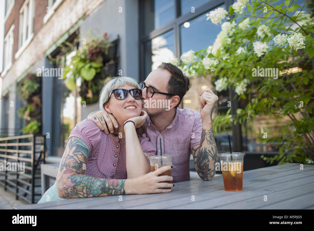 Young couple sitting in outdoor cafe drinking ice tea Stock Photo - Alamy