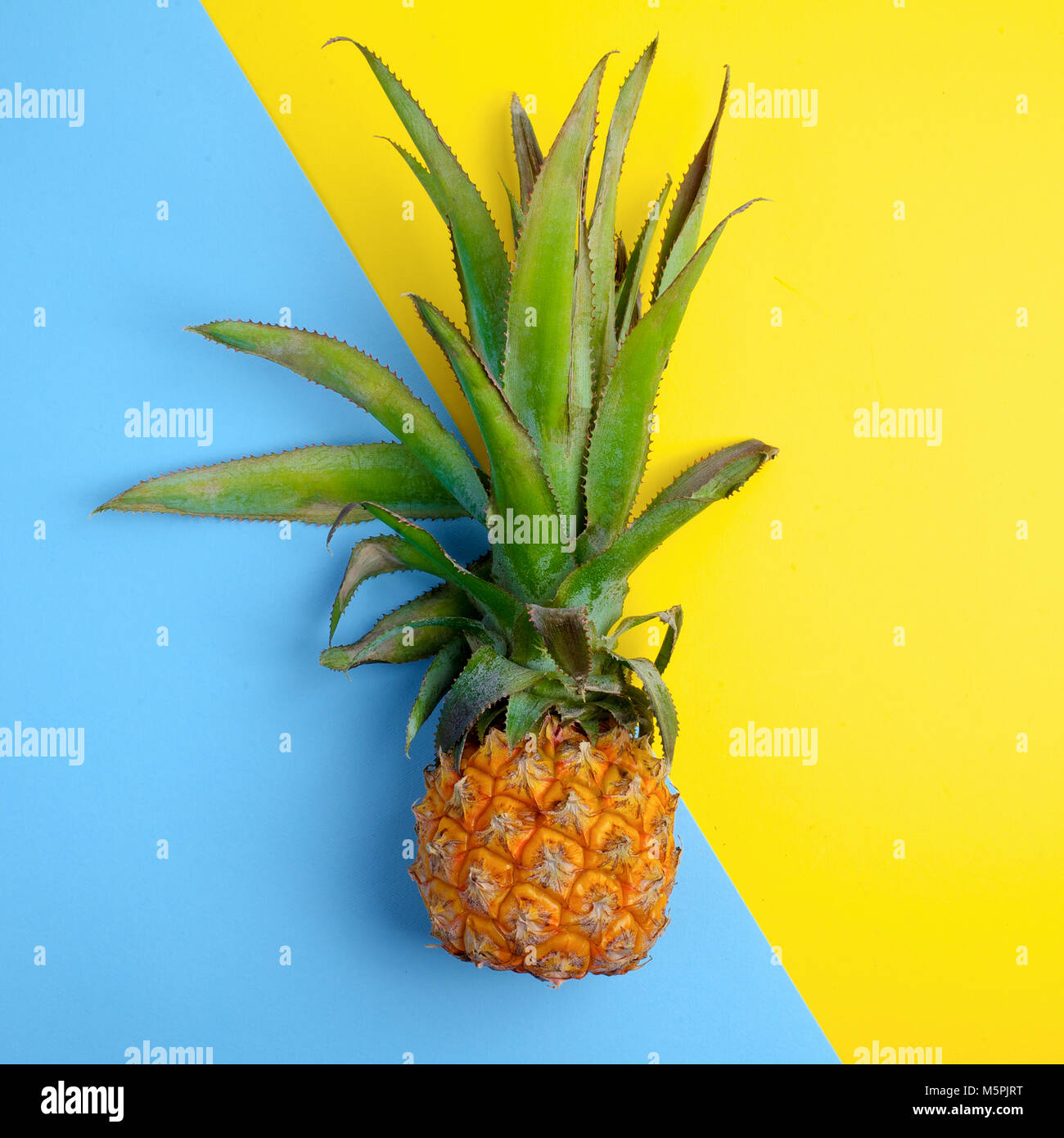 Pineapple fruit on a bright yellow and blue background. Top view Stock ...