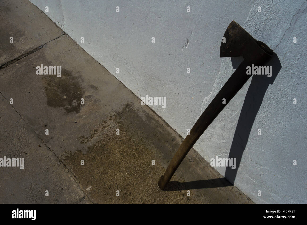 Old and dirty axe or ax resting on a white wall. Image of a rural place ...