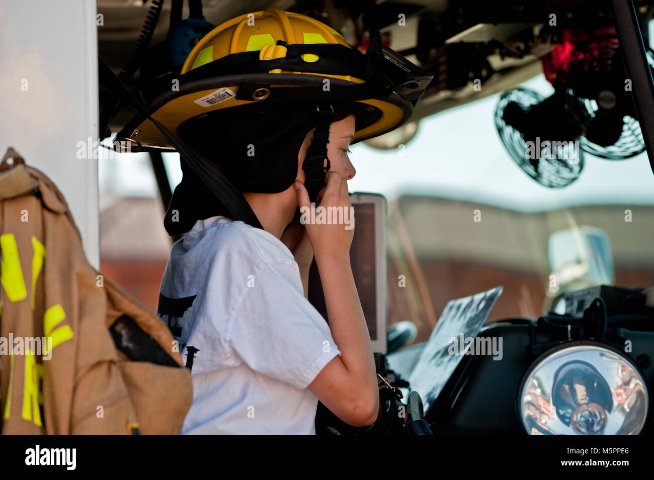 A boy inside a fire truck trying on a firefighter helmet Stock Photo ...