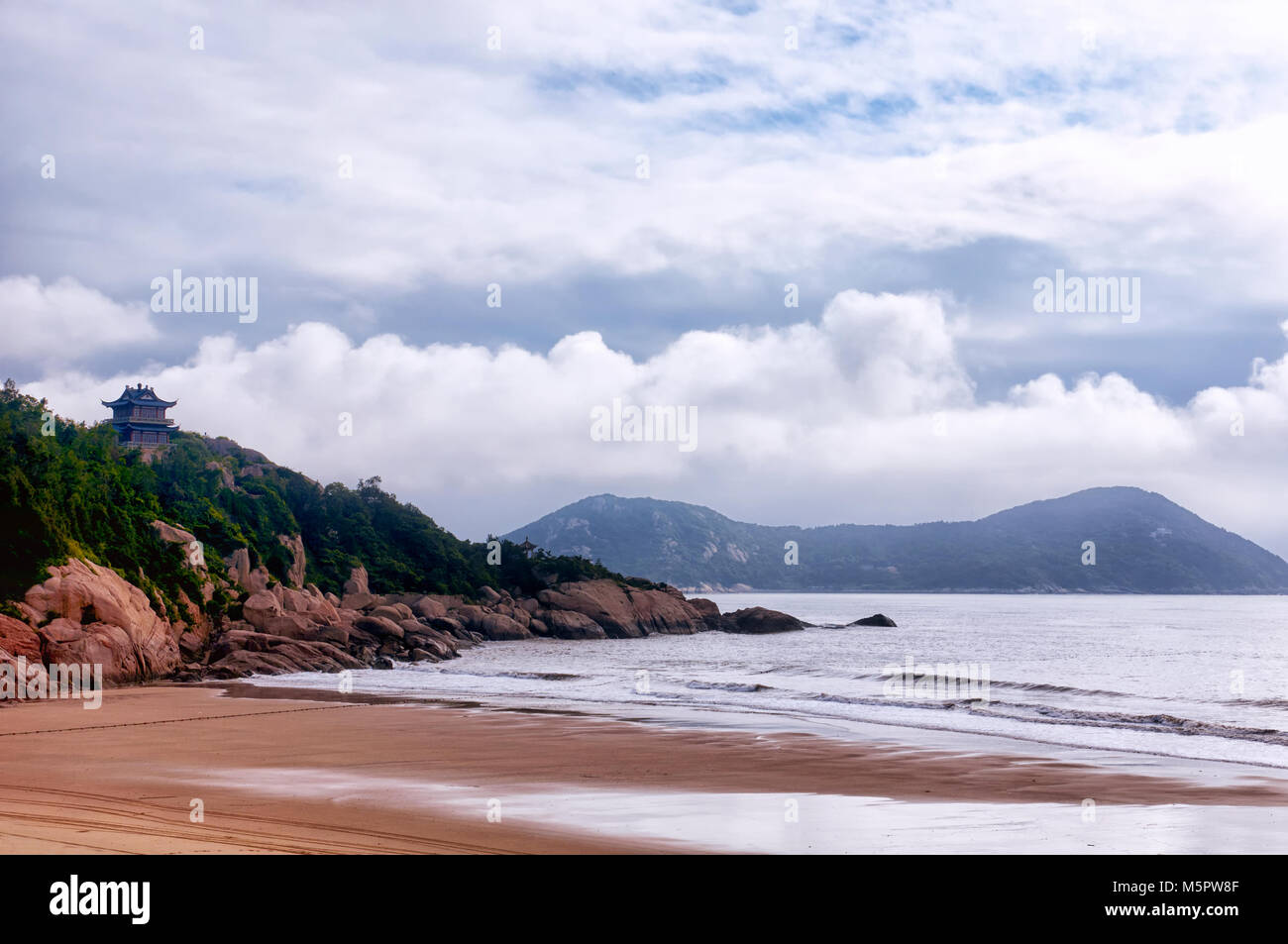 A Chinese building and rocky shore at 100 step beach at low tide on the ...