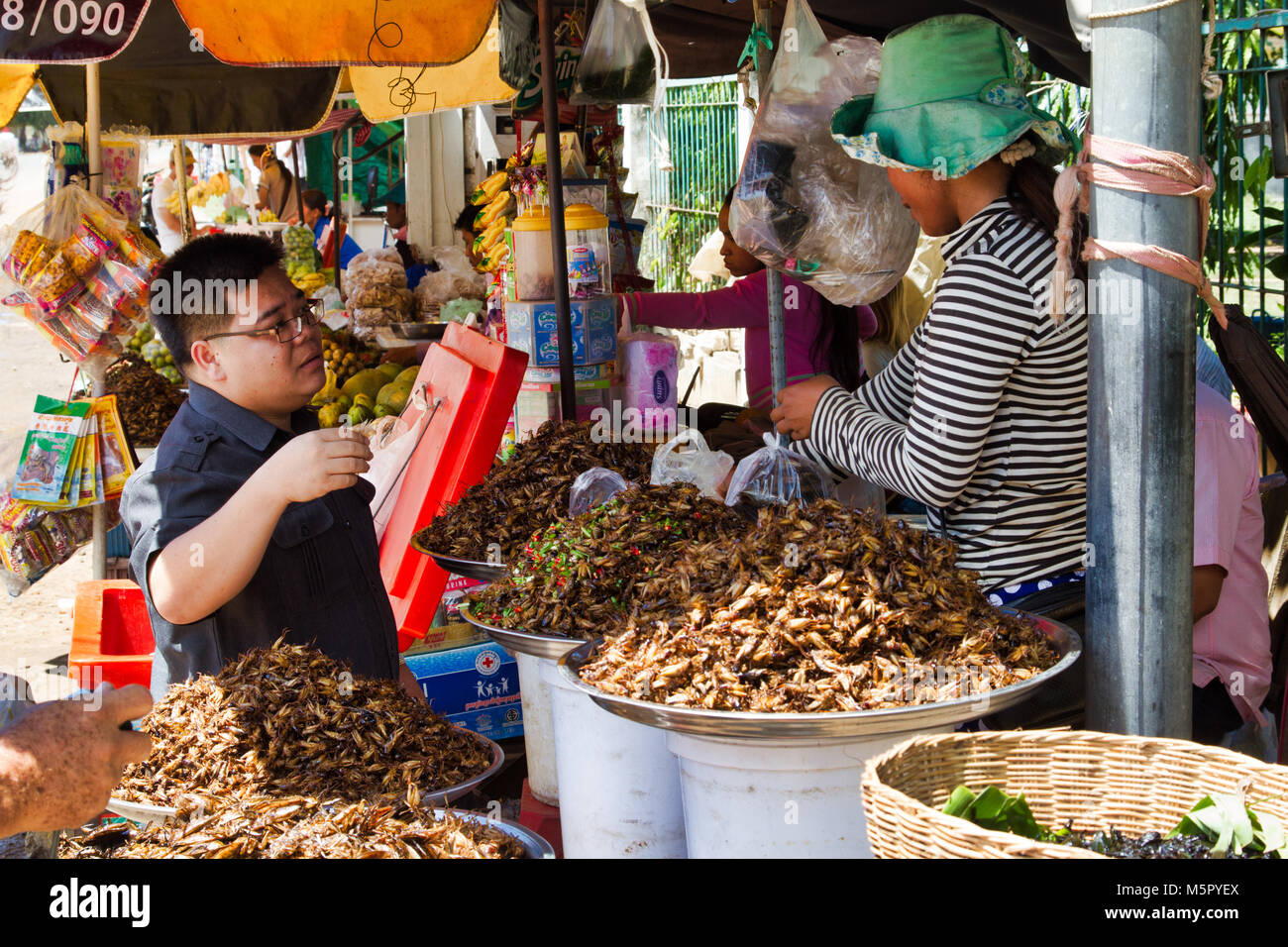 A customer buys a bag of cooked, seasoned insects from a food vendor in ...
