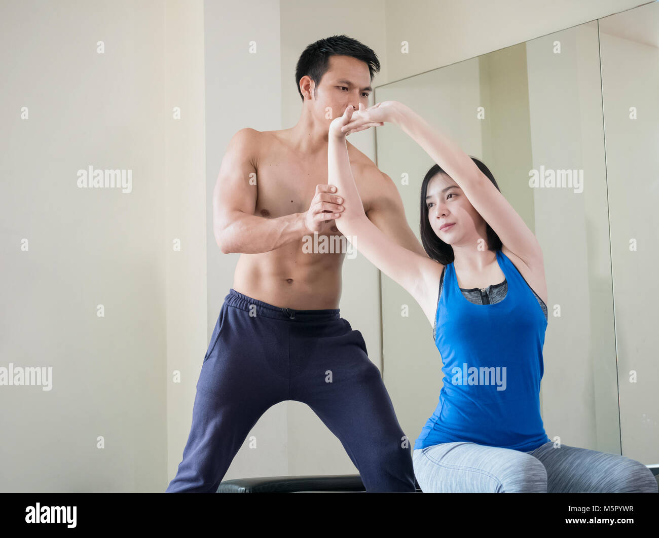Sport women with trainer stretching muscle in the gym Stock Photo - Alamy