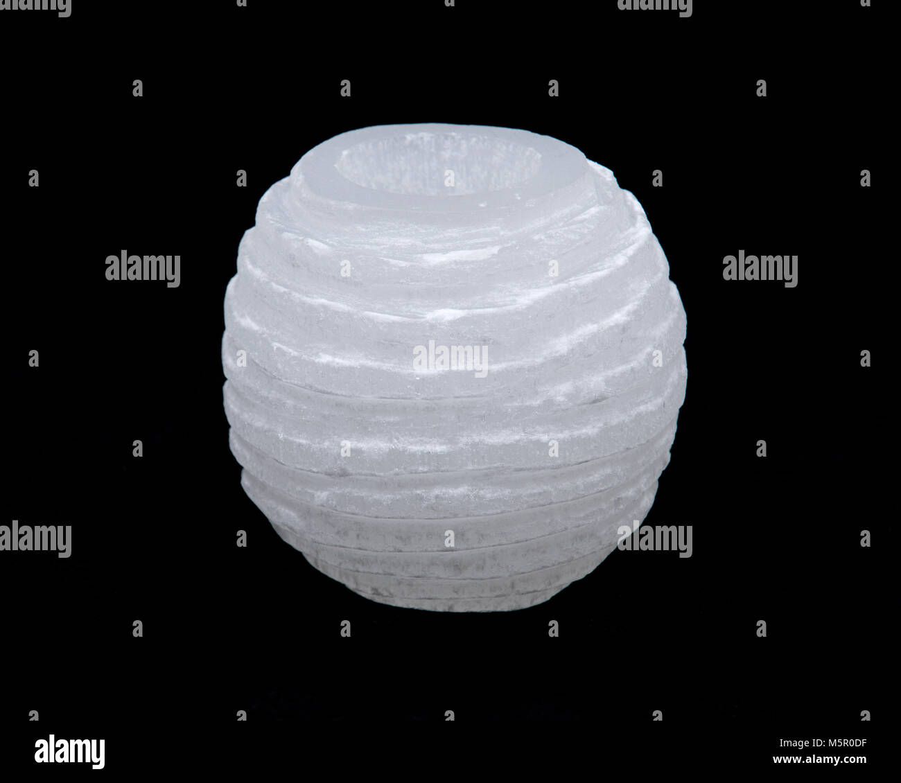 White selenite cylinder tea light holder on black background Stock ...