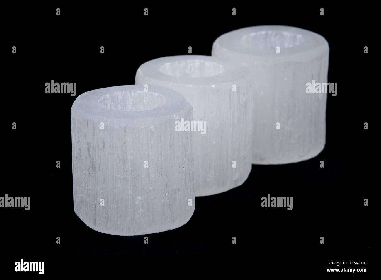 White selenite cylinder tea light holder on black background Stock ...