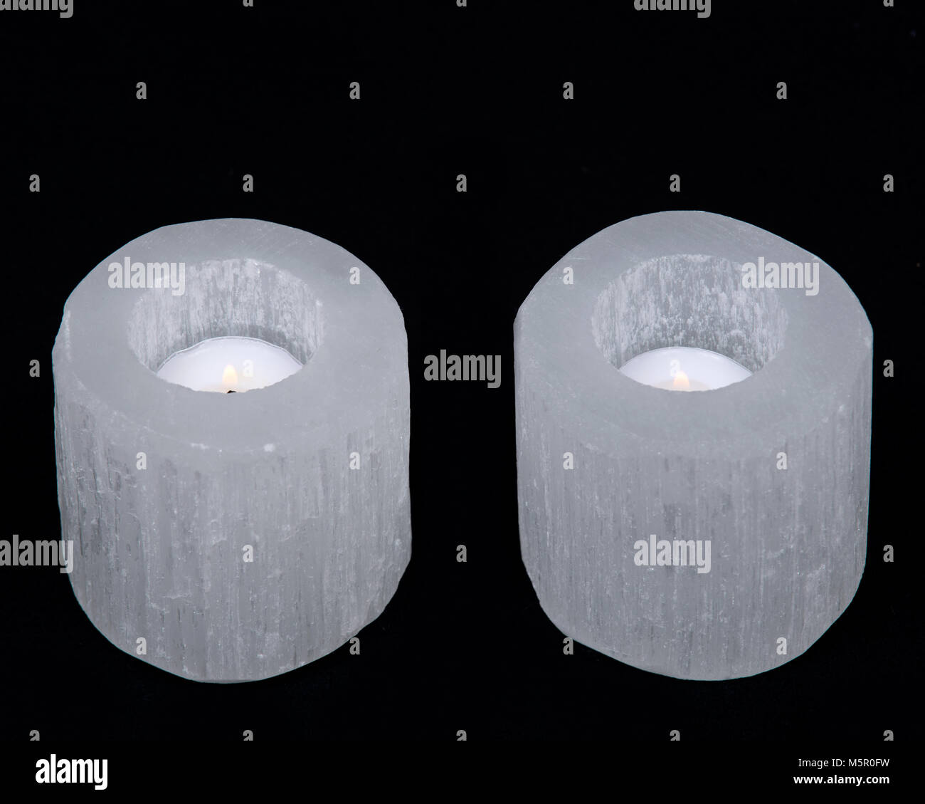 White selenite cylinder tea light holder on black background Stock ...