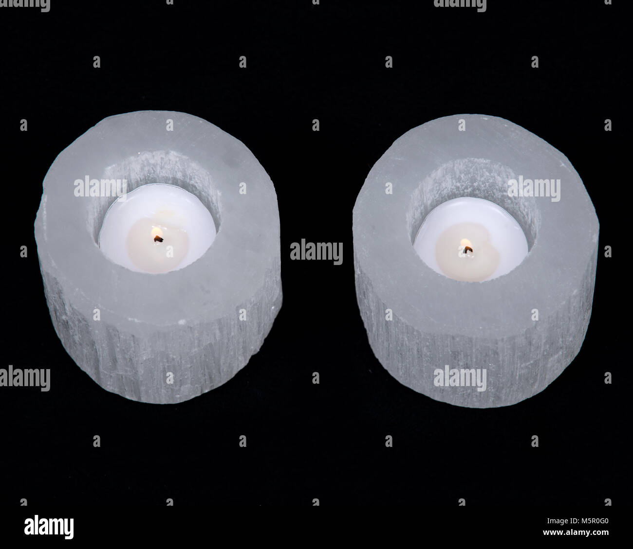 White selenite cylinder tea light holder on black background Stock ...