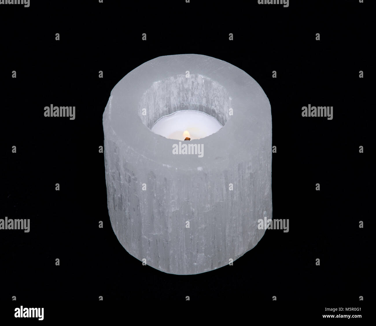 White selenite cylinder tea light holder on black background Stock ...