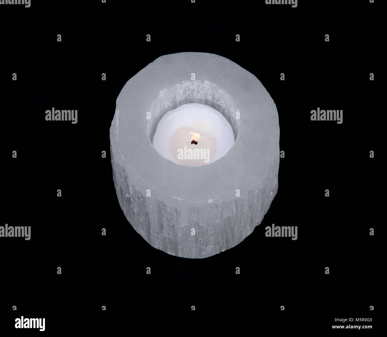 White selenite cylinder tea light holder on black background Stock ...