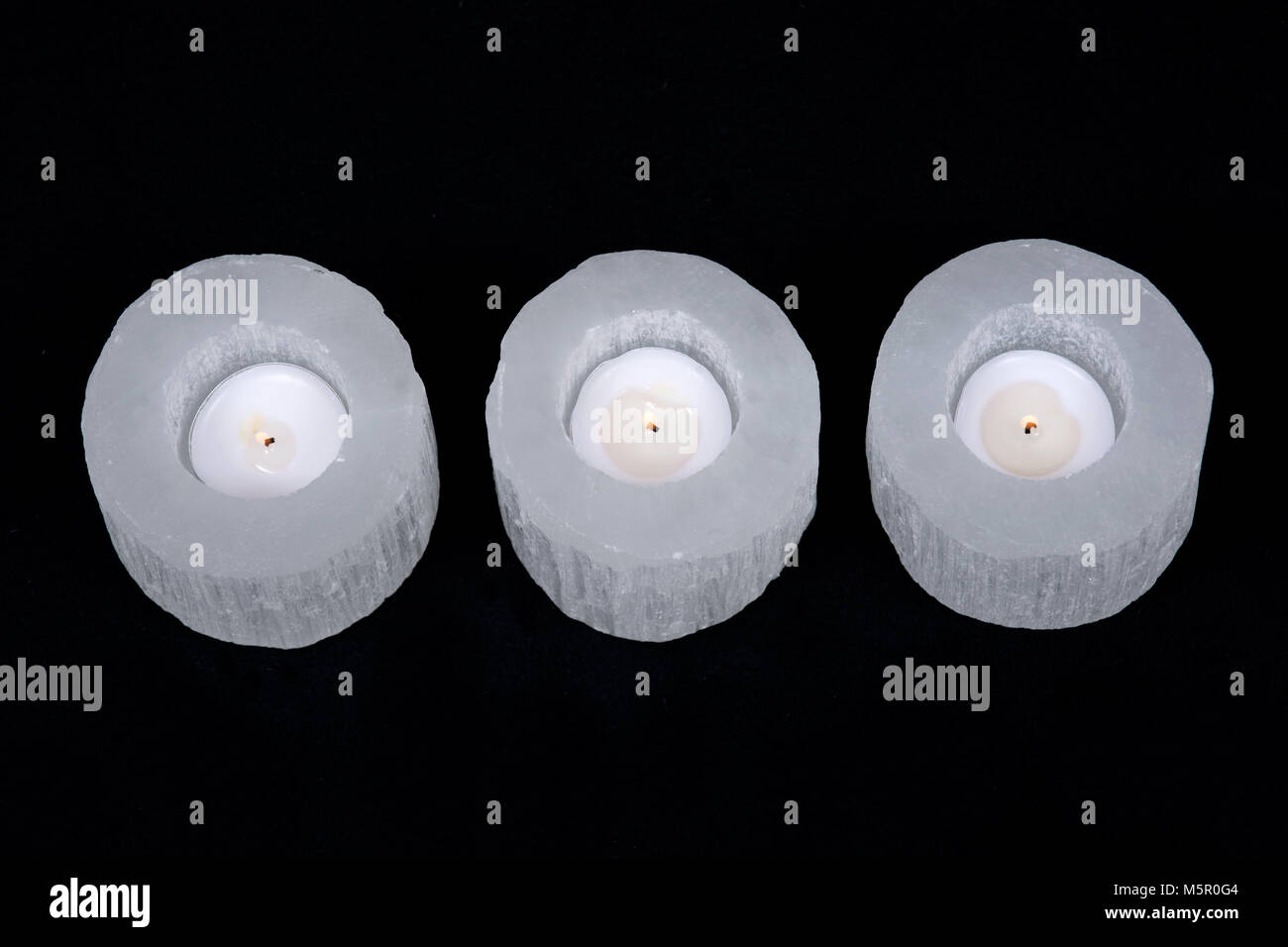 White selenite cylinder tea light holder on black background Stock ...