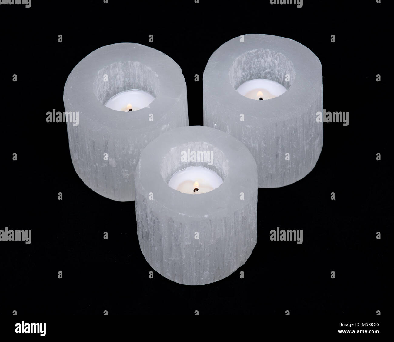 White selenite cylinder tea light holder on black background Stock ...