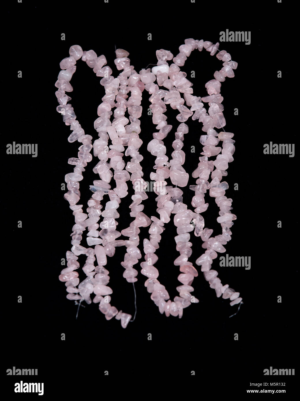 Polished rose quartz strings on black background Stock Photo - Alamy