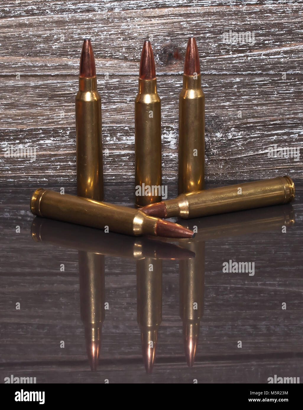 Five rifle bullets in front of a wooden background placed upon a ...