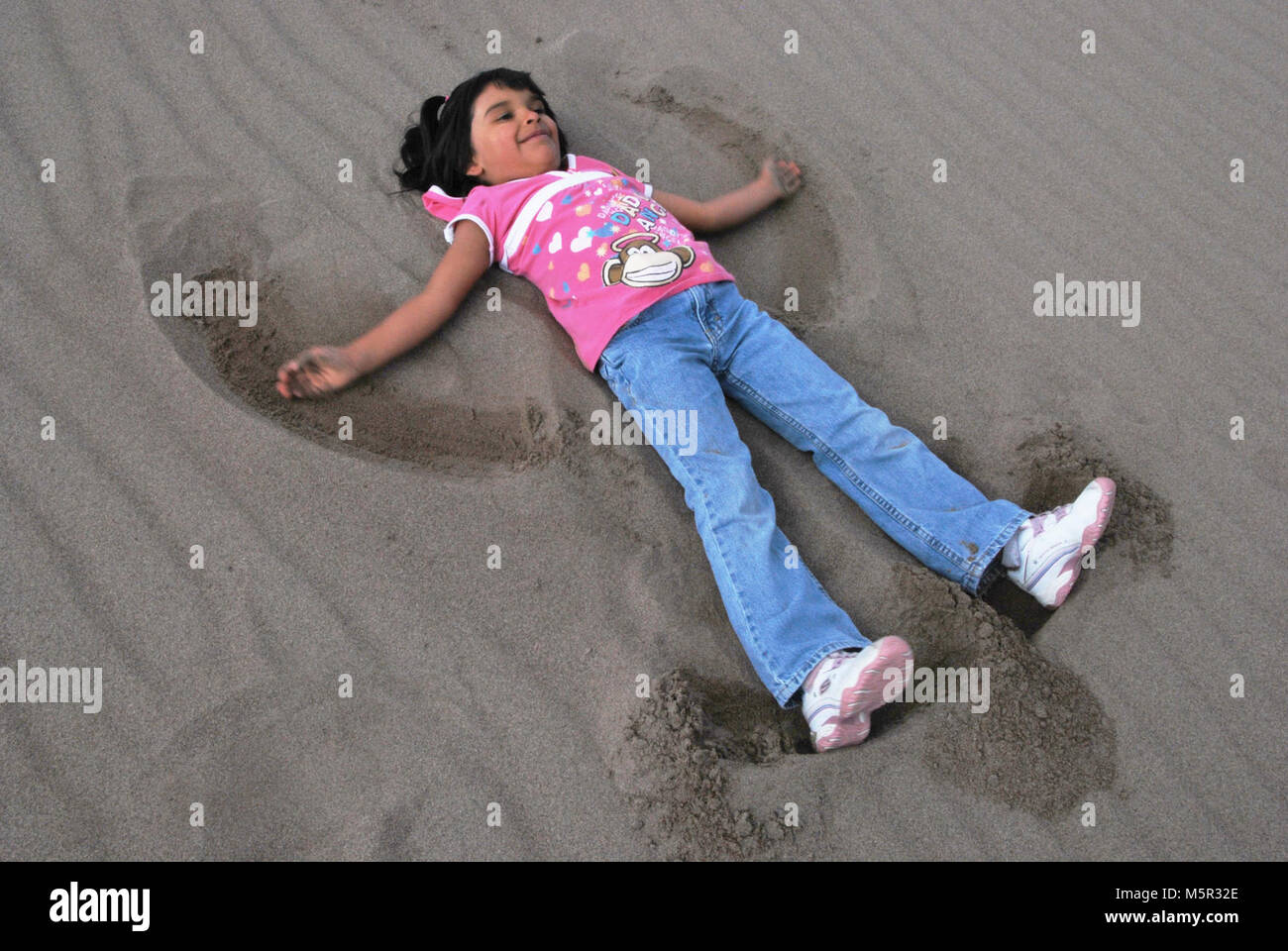 Girl Making a Sand Angel Stock Photo - Alamy