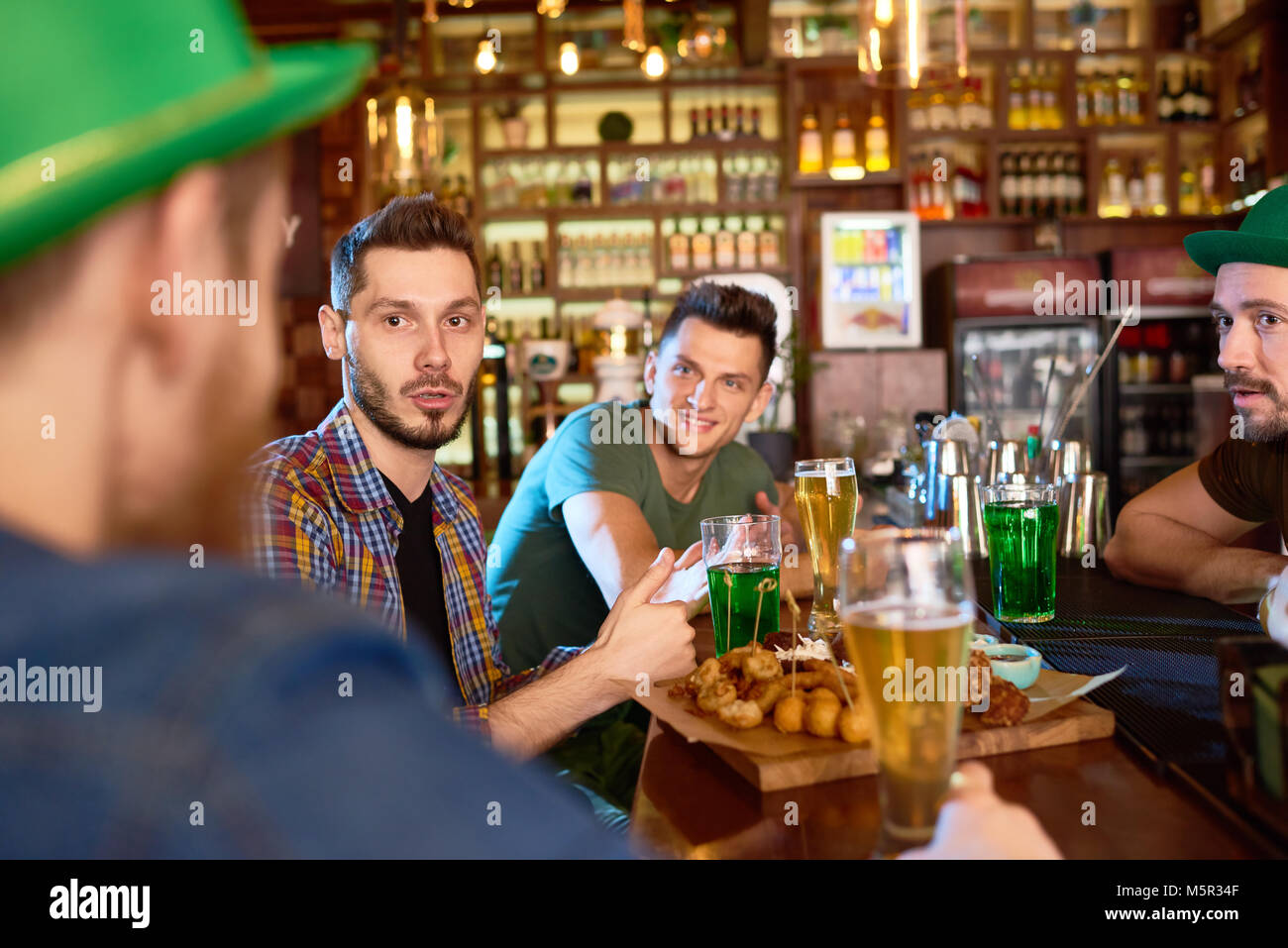 Group of young men chatting animatedly with each other and drinking ...