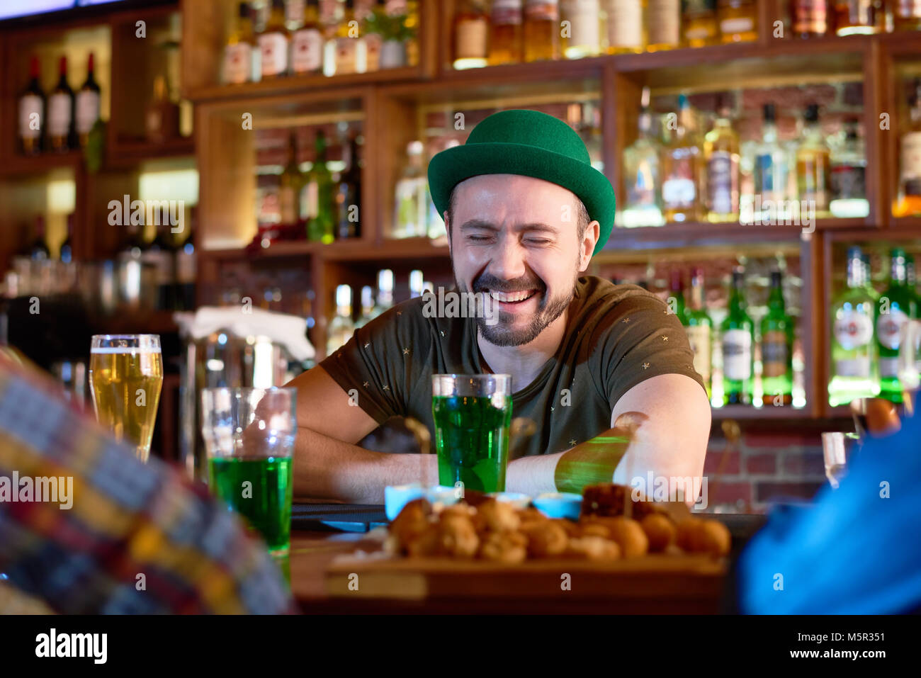 Head and shoulders portrait of cheerful bearded barman wearing green ...