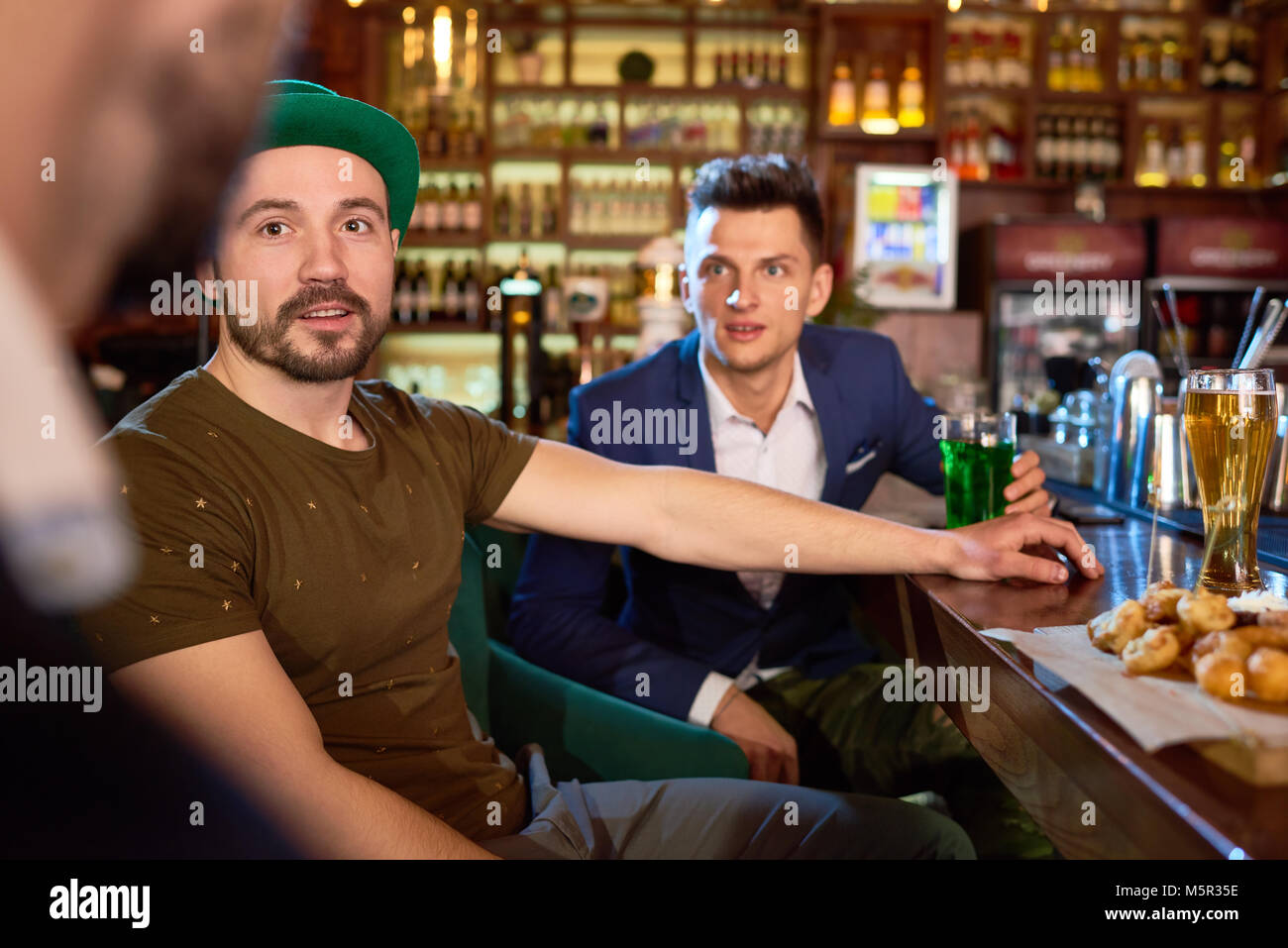 Group of young friends wrapped up in small talk while sitting at bar ...