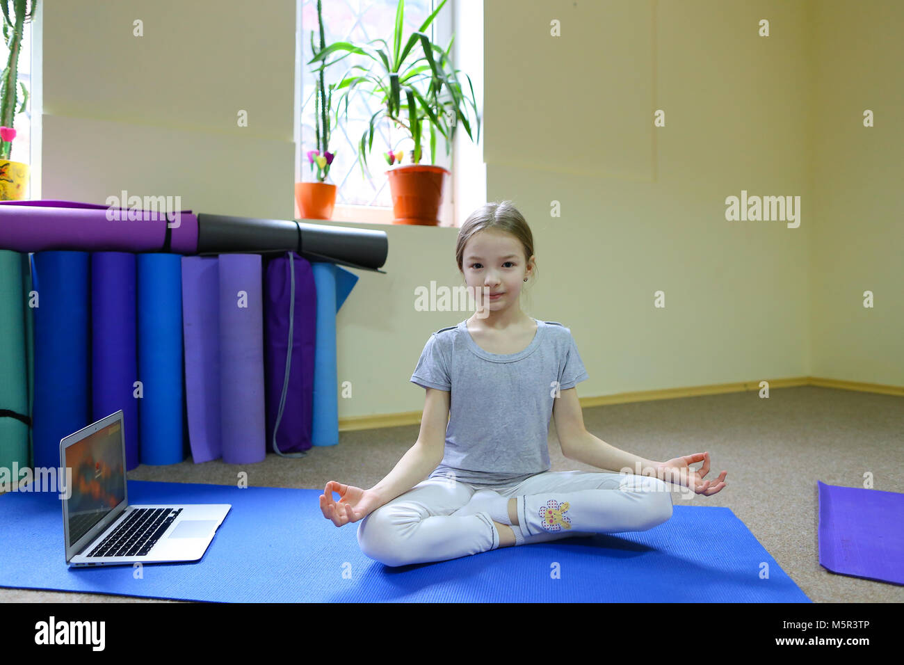 Little girl sits on floor in lotus position Stock Photo - Alamy