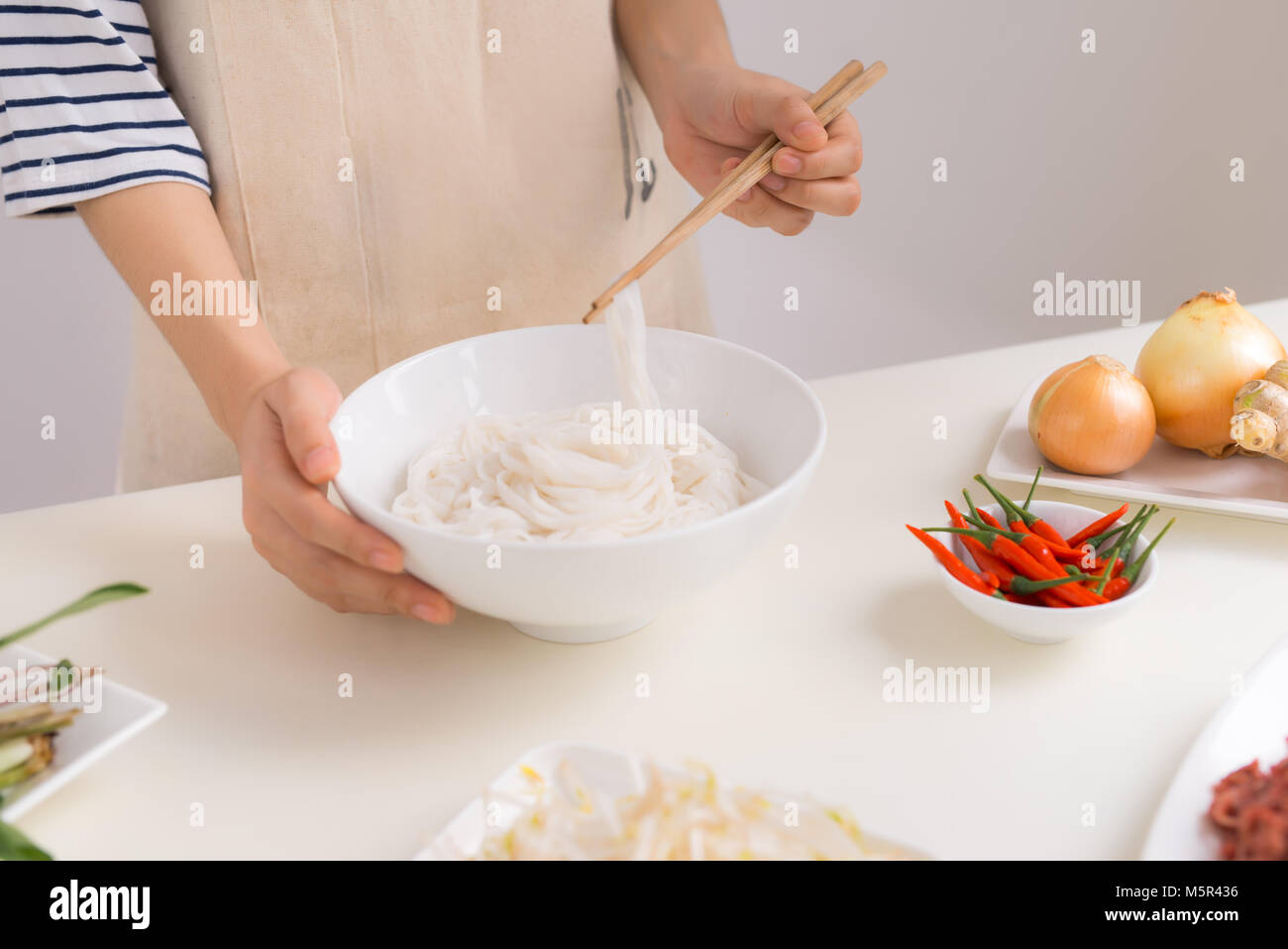 Female chef prepare traditional Vietnamese soup Pho bo with herbs, meat ...