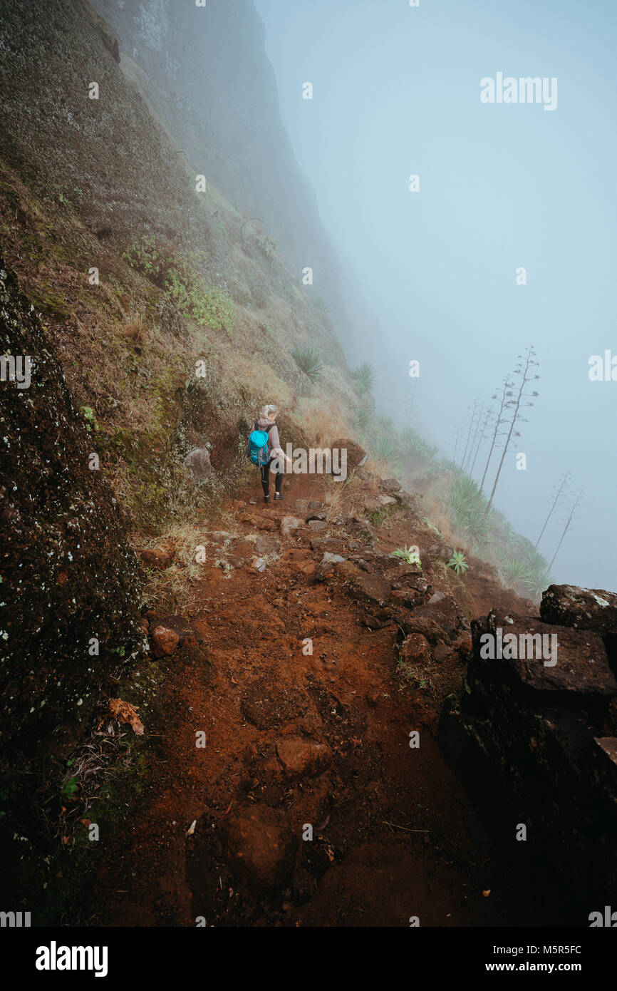 Hiker women with backpack walking down the steep slope of the rock in ...