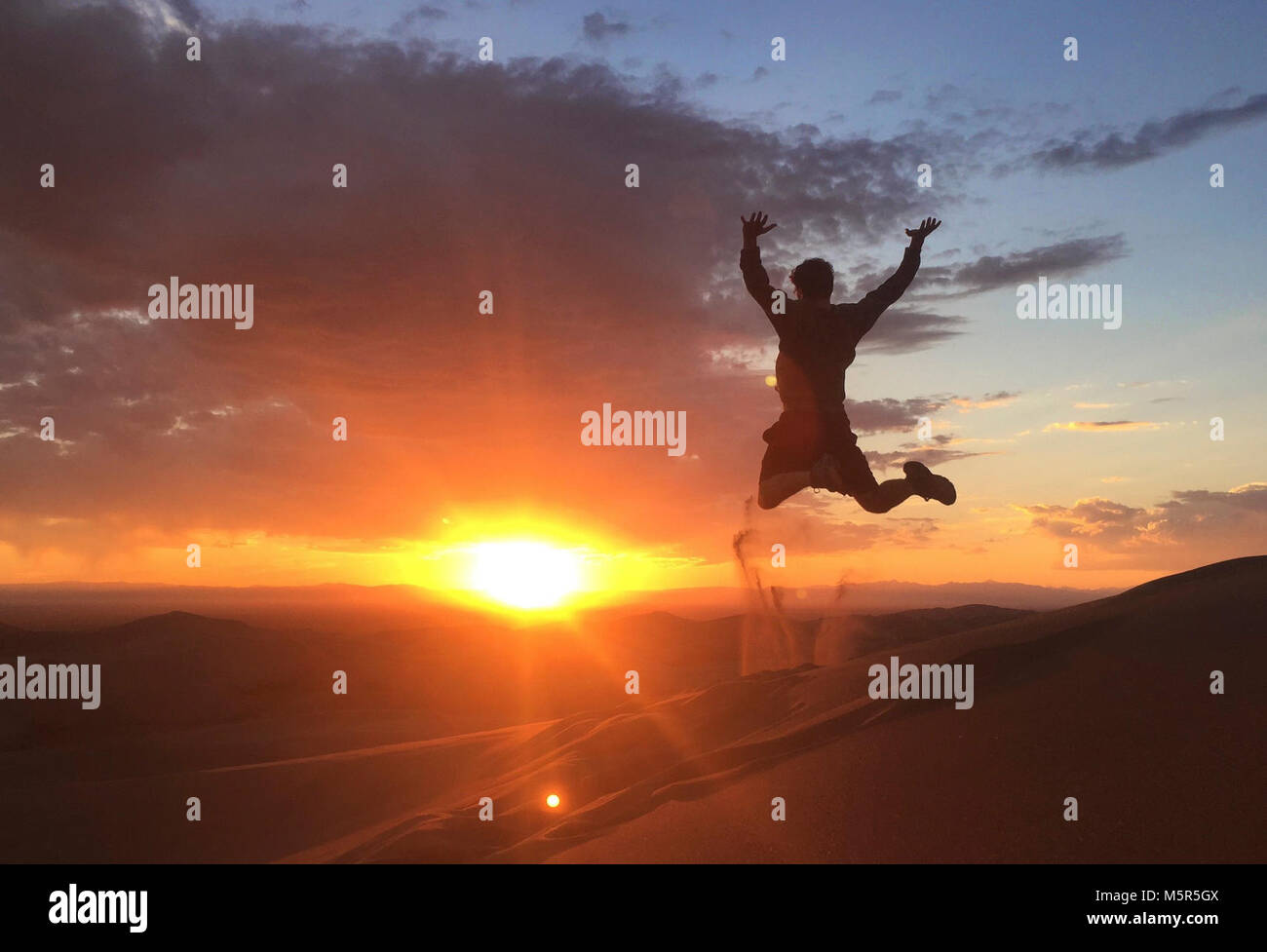 Man Jumping Off Star Dune at Sunset Stock Photo - Alamy