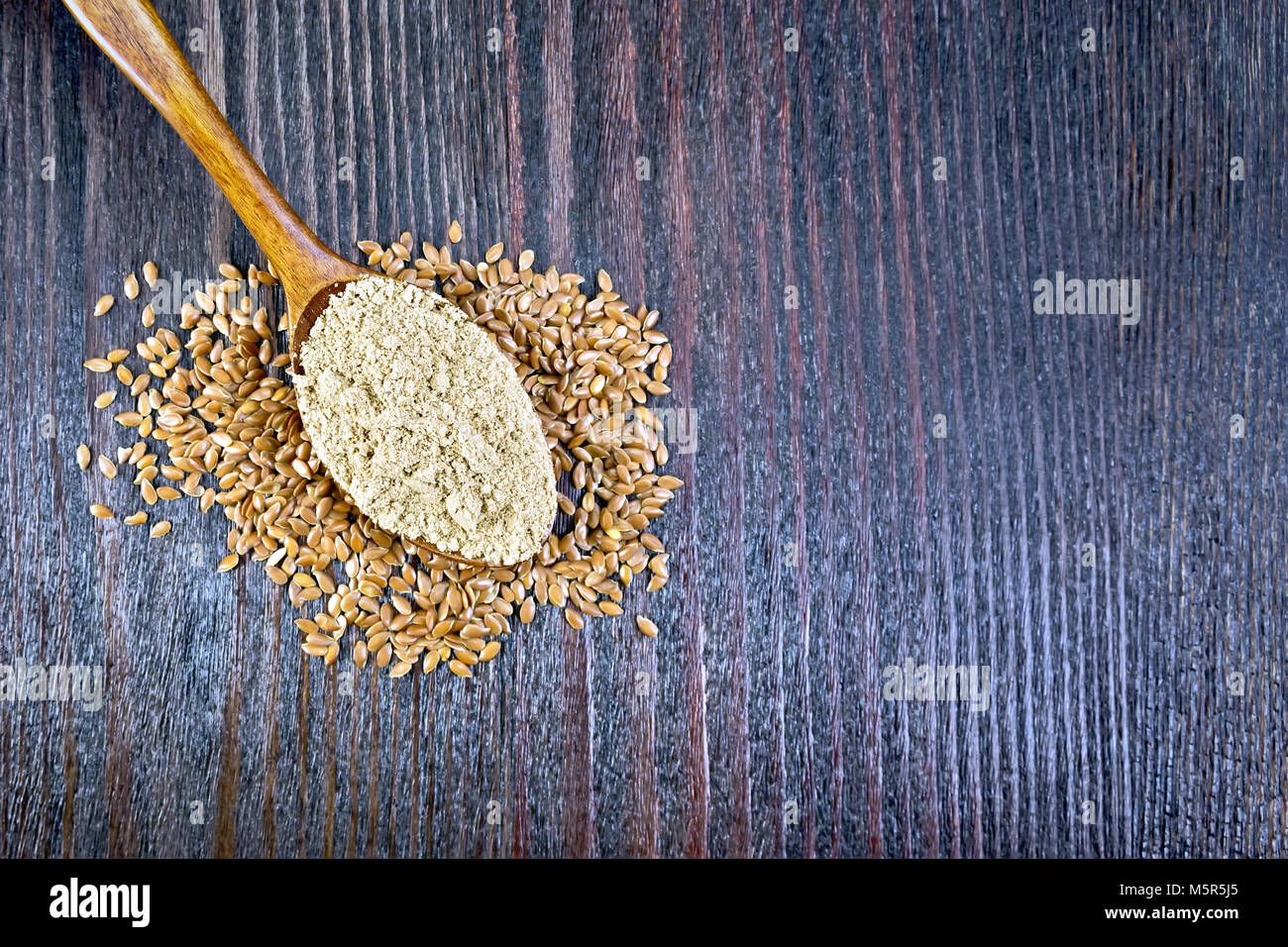 Flax flour in a spoon, seeds on a table on a background of a wooden ...