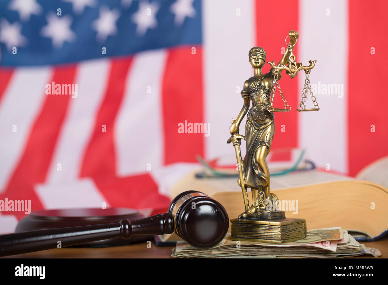 Statue of Themis on a pile of banknotes. Closeup. Flag of USA in the ...
