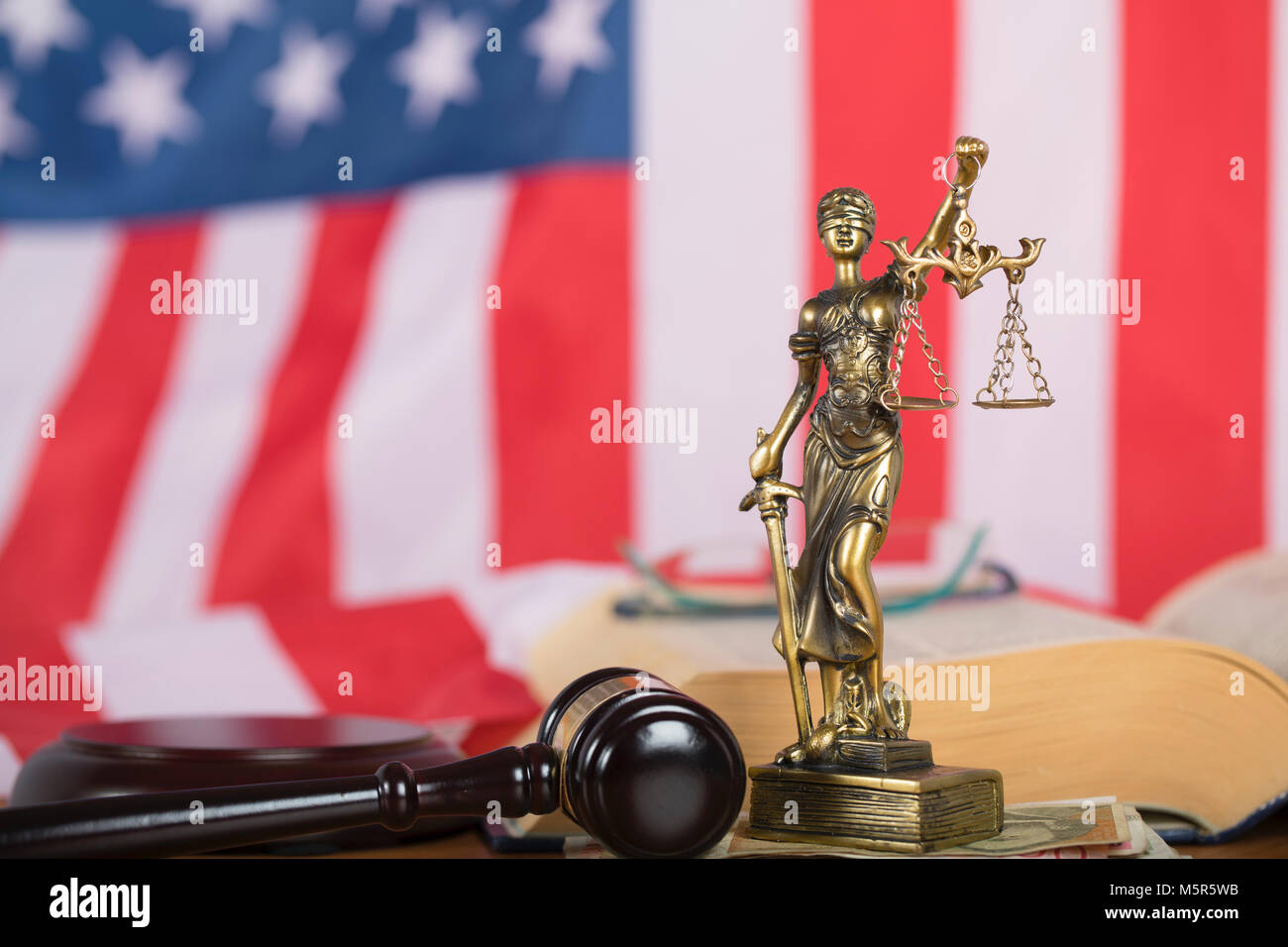 Statue of Themis on a pile of banknotes. Closeup. Flag of USA in the ...