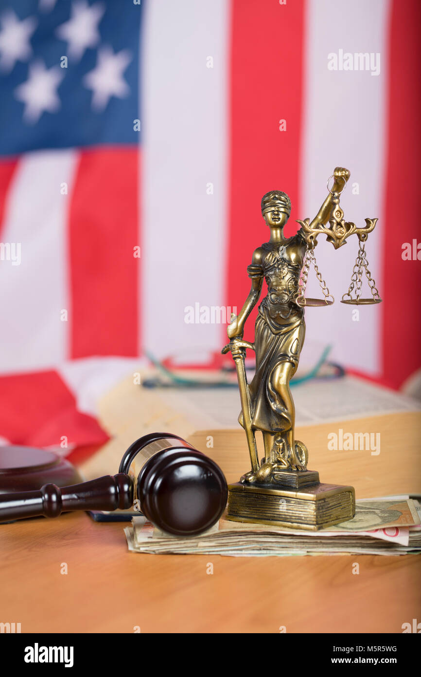Statue of Themis on a pile of banknotes. Closeup. Flag of USA in the ...