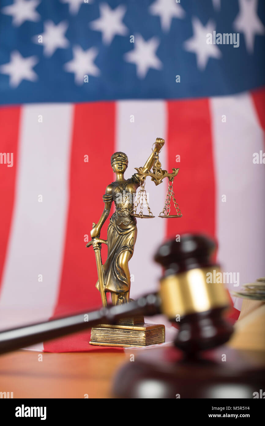 Statue of Themis. Judge's gavel, and flag of USA in the background ...