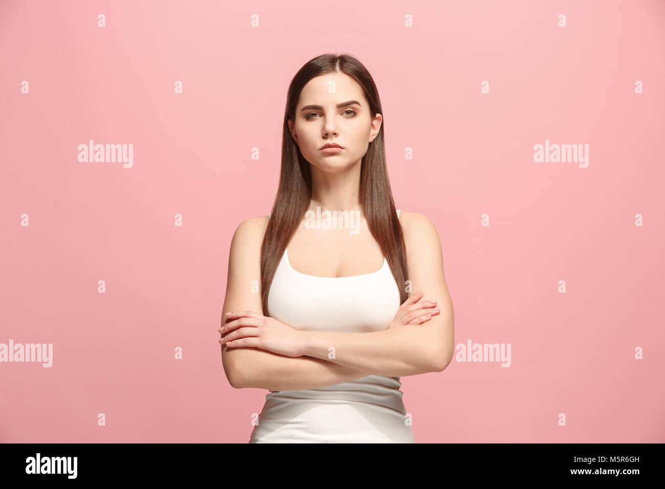 The serious business woman standing and looking at camera against pink ...