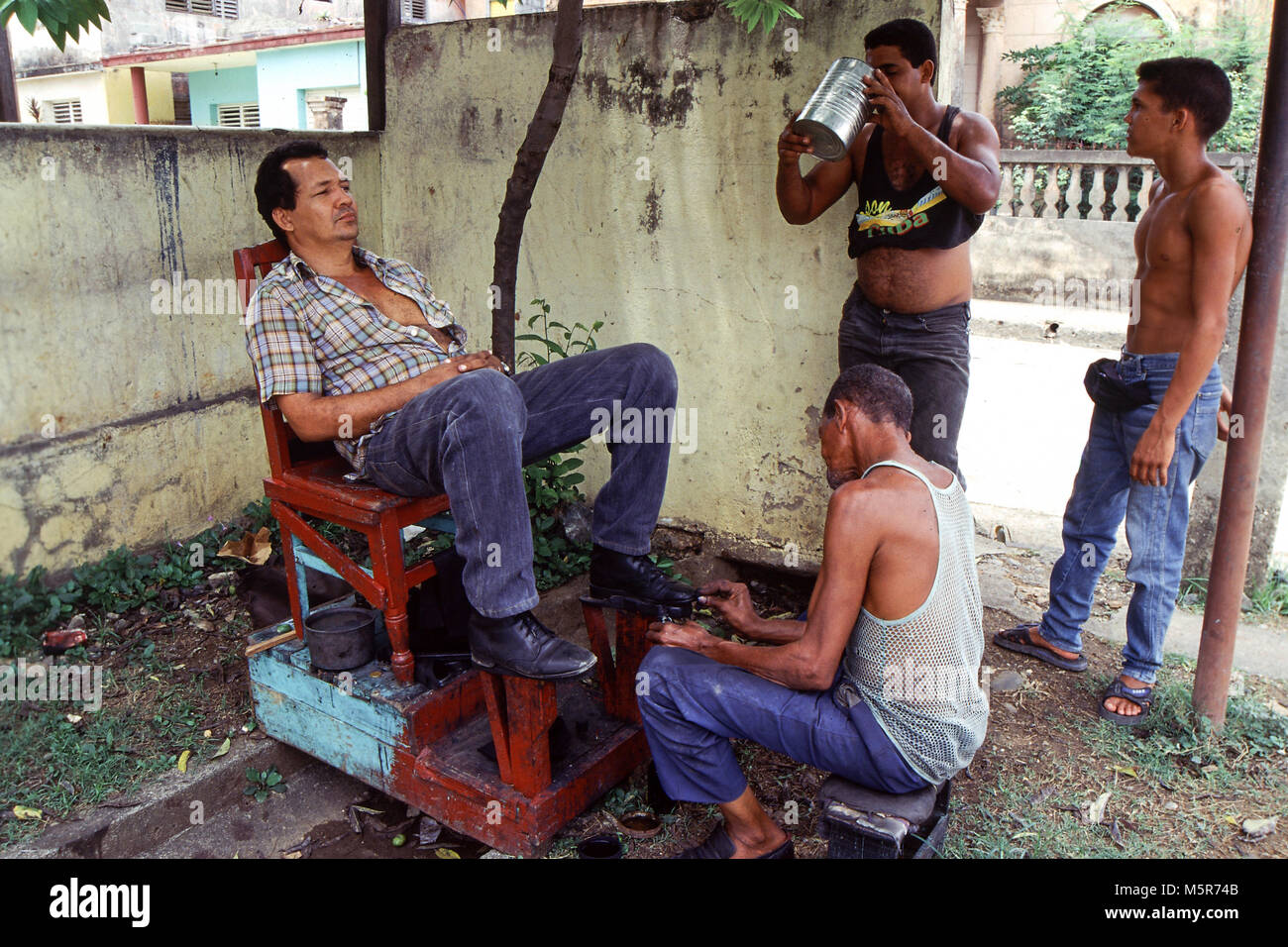 A shoeshiner cleaning the shoes of a customer in Trinidad, Cuba during ...